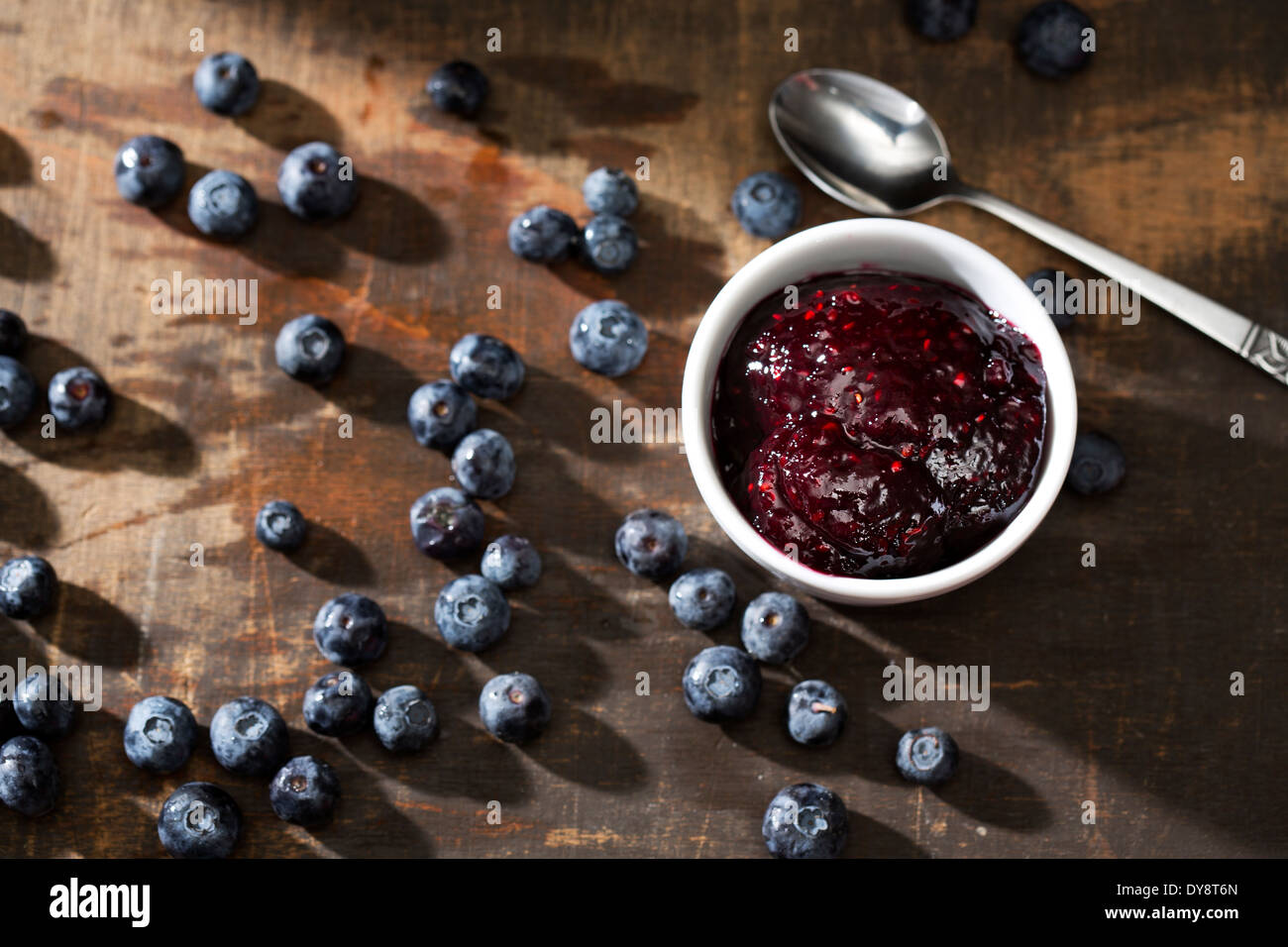 Bowl of blueberry and raspberry jam, spoon and blueberries on dark ...