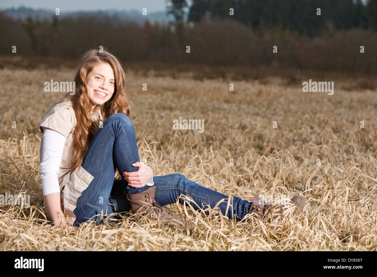 Portrait of smiling teenage girl sitting on field Stock Photo - Alamy