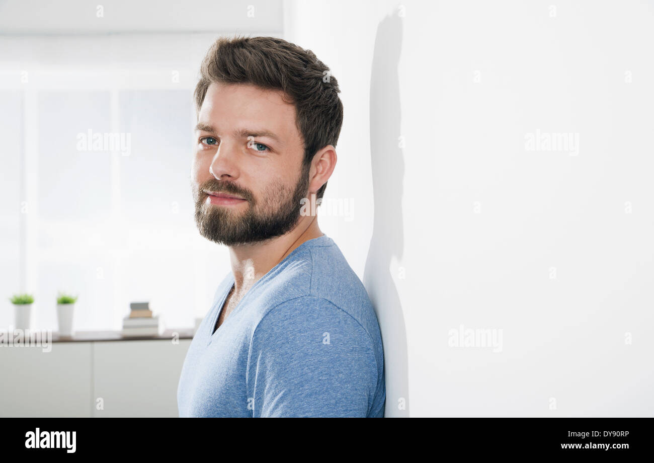 Portrait of young serious looking man leaning against wall Stock Photo ...