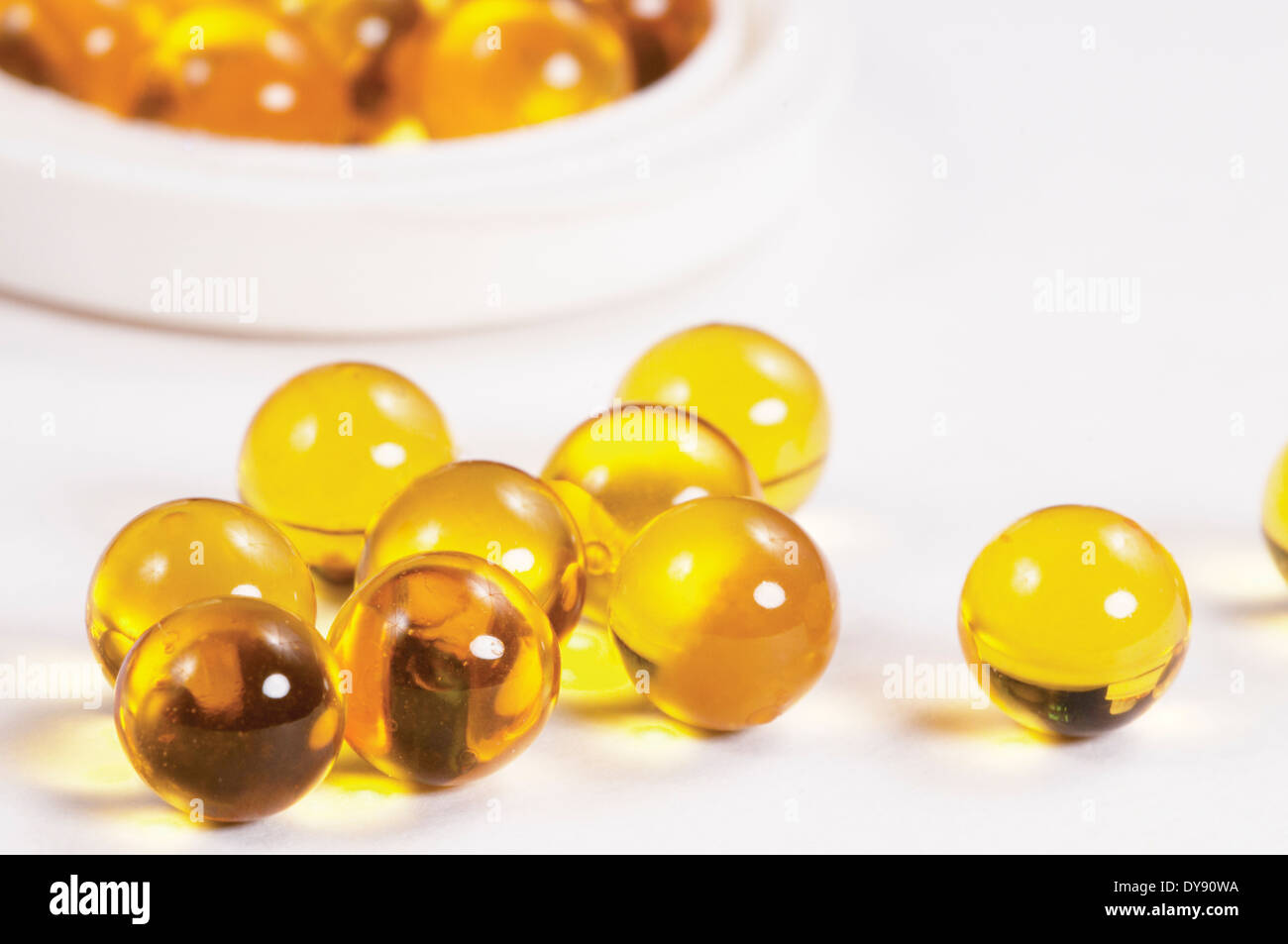 Yellow capsules near the box over light background Stock Photo - Alamy