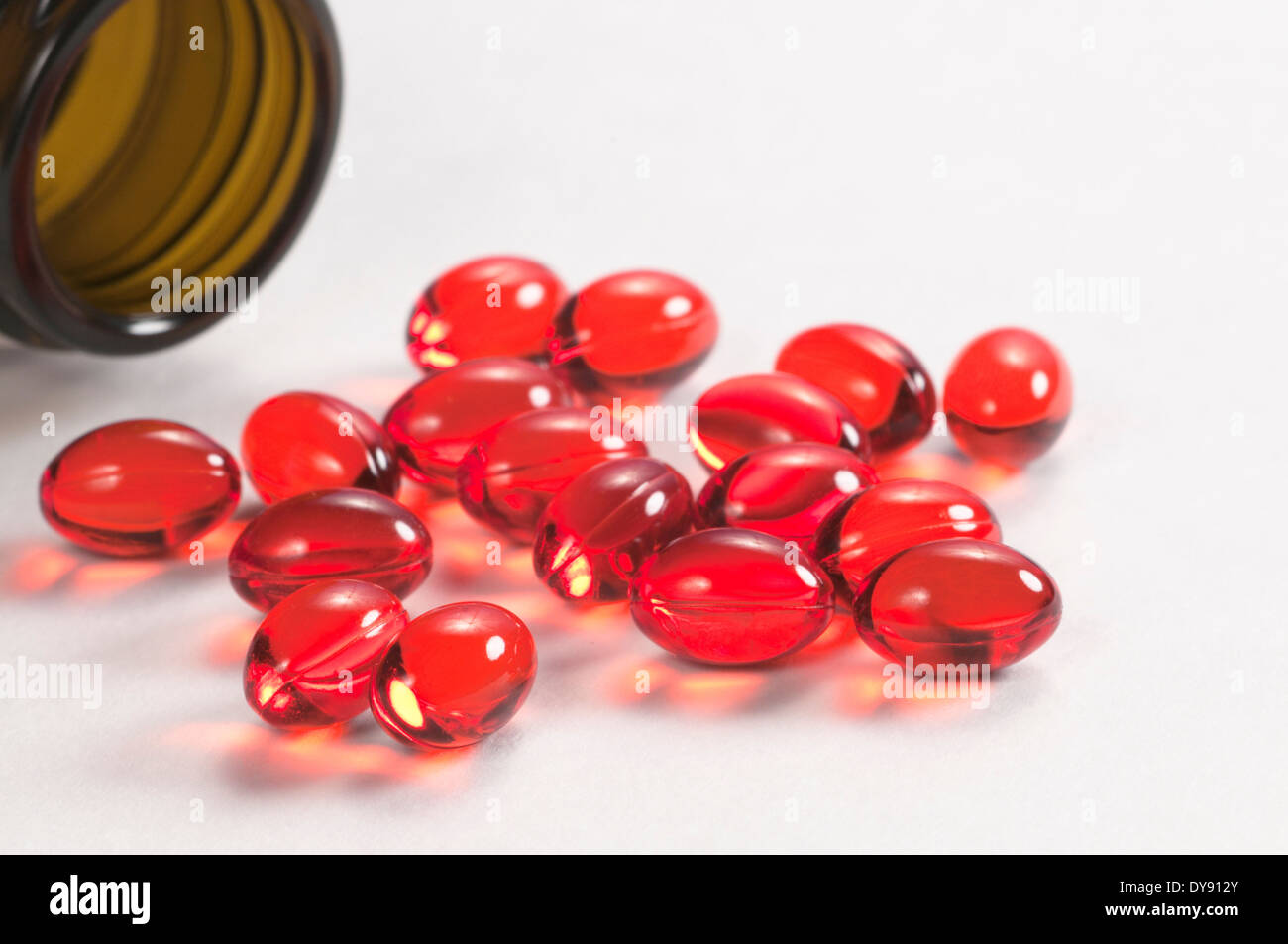 Red capsules near the box over light background Stock Photo - Alamy