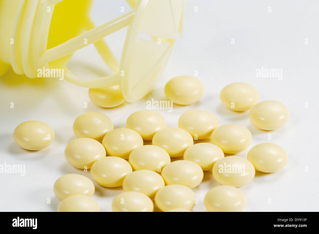 Yellow tablets near the box over light background Stock Photo - Alamy
