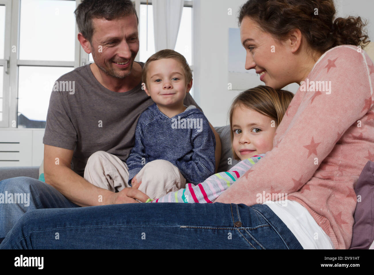 Happy family of four sitting on couch Stock Photo - Alamy