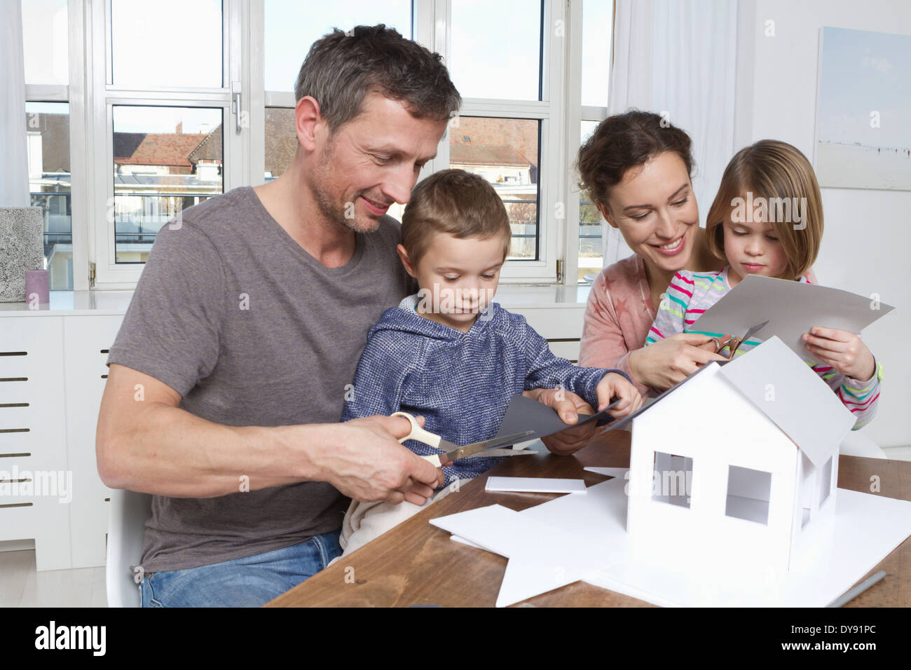 Family of four constructing house model Stock Photo - Alamy