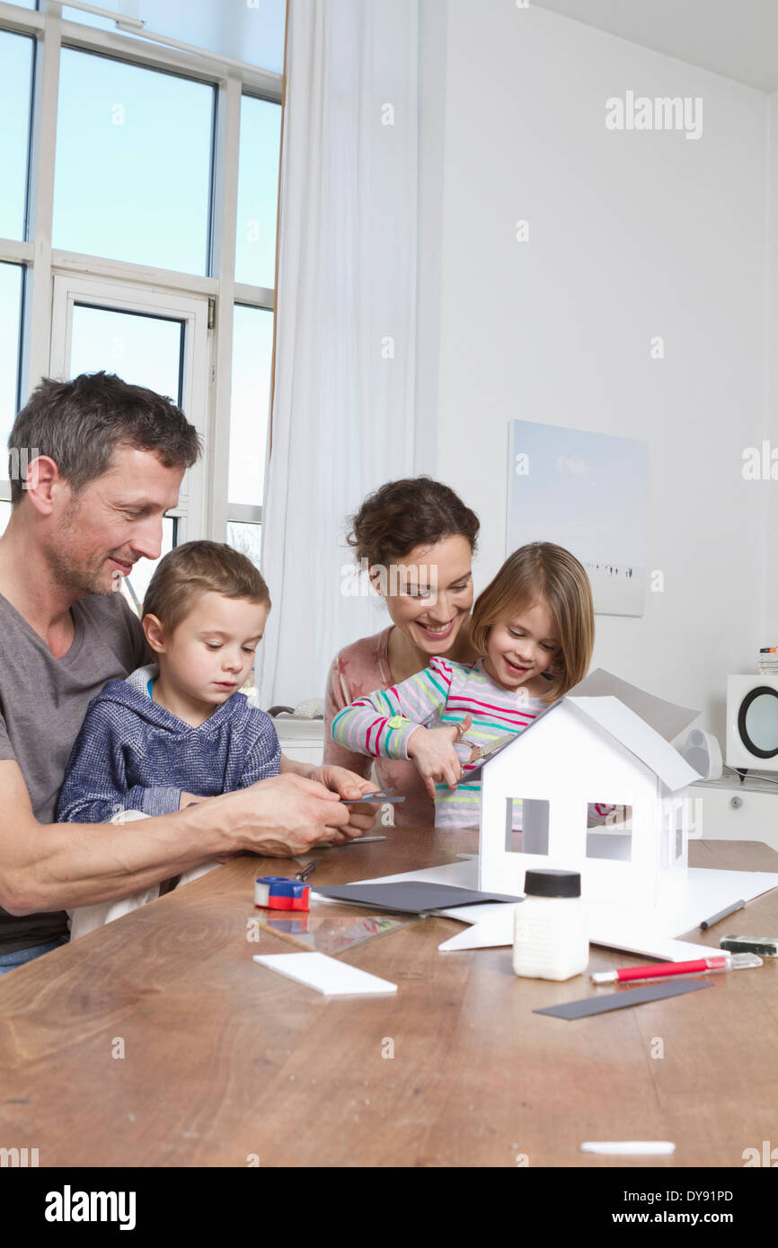 Family of four constructing house model Stock Photo - Alamy
