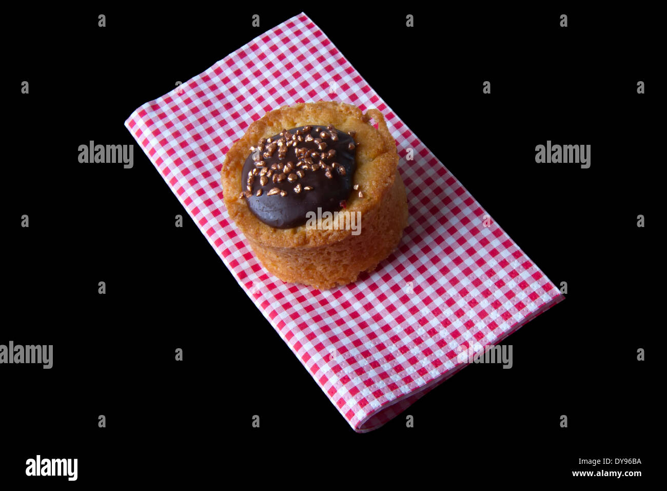 Home baked chocolate iced individual sponge cake on a gingham patterned ...