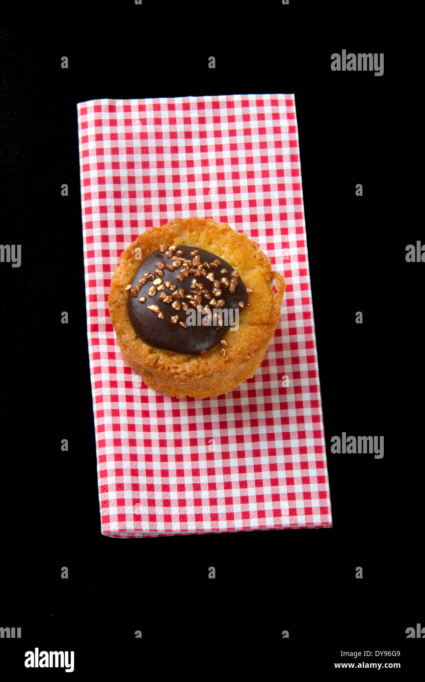 Home baked chocolate iced individual sponge cake on a gingham patterned ...
