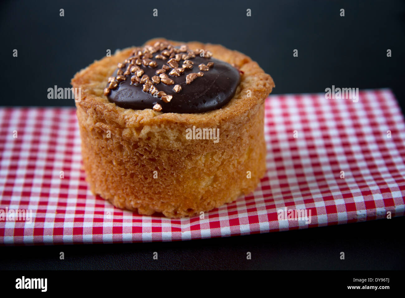 Home baked chocolate iced individual sponge cake on a gingham patterned ...