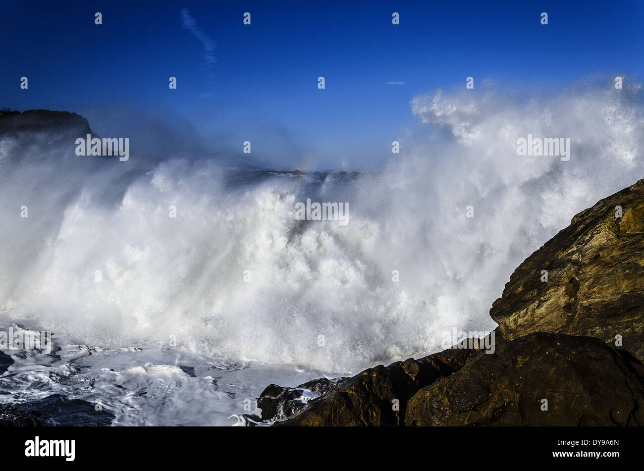 Splashing wave into the rocks Stock Photo - Alamy