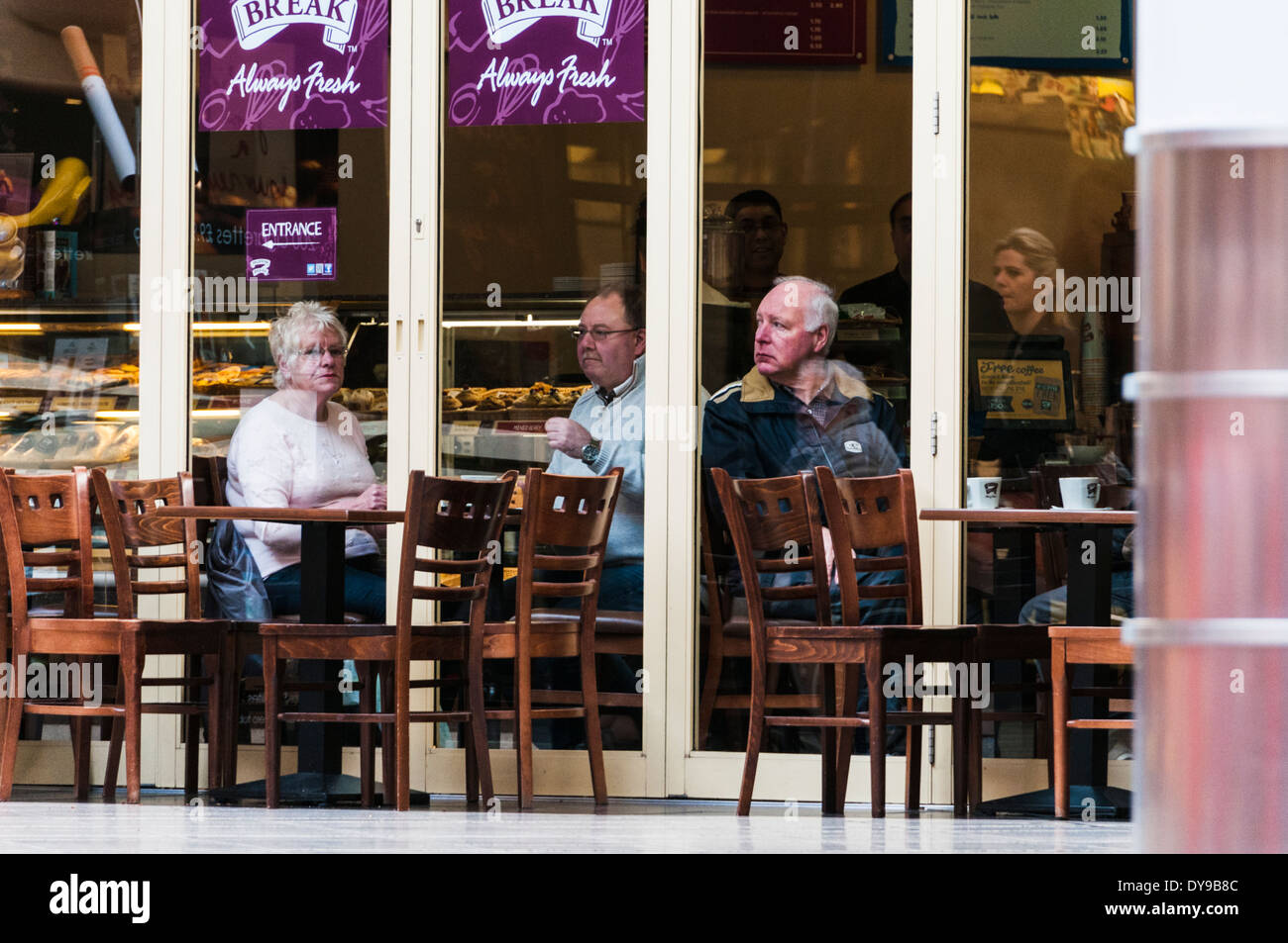Adults sitting inside a glass fronted coffee shop Stock Photo - Alamy