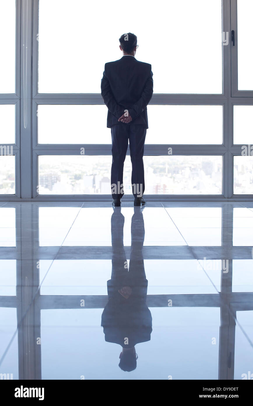 Businessman standing window looking distance hi-res stock photography ...