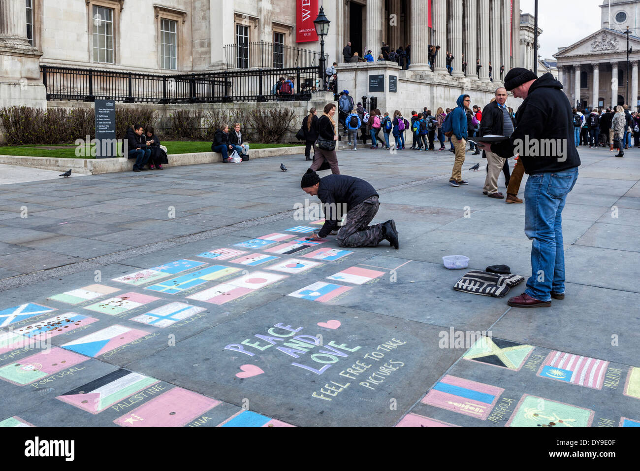 Street artists draw flags on paving and tourists place coins on the ...