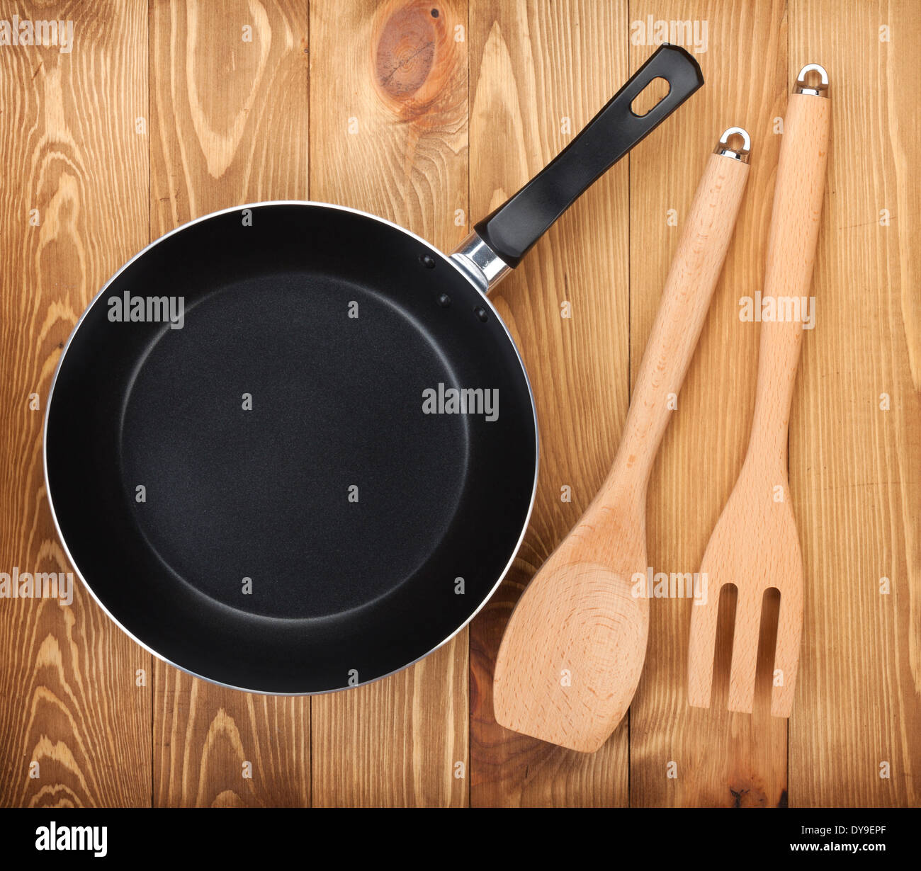 Frying pan and kitchen utensils on wooden table background. View from ...