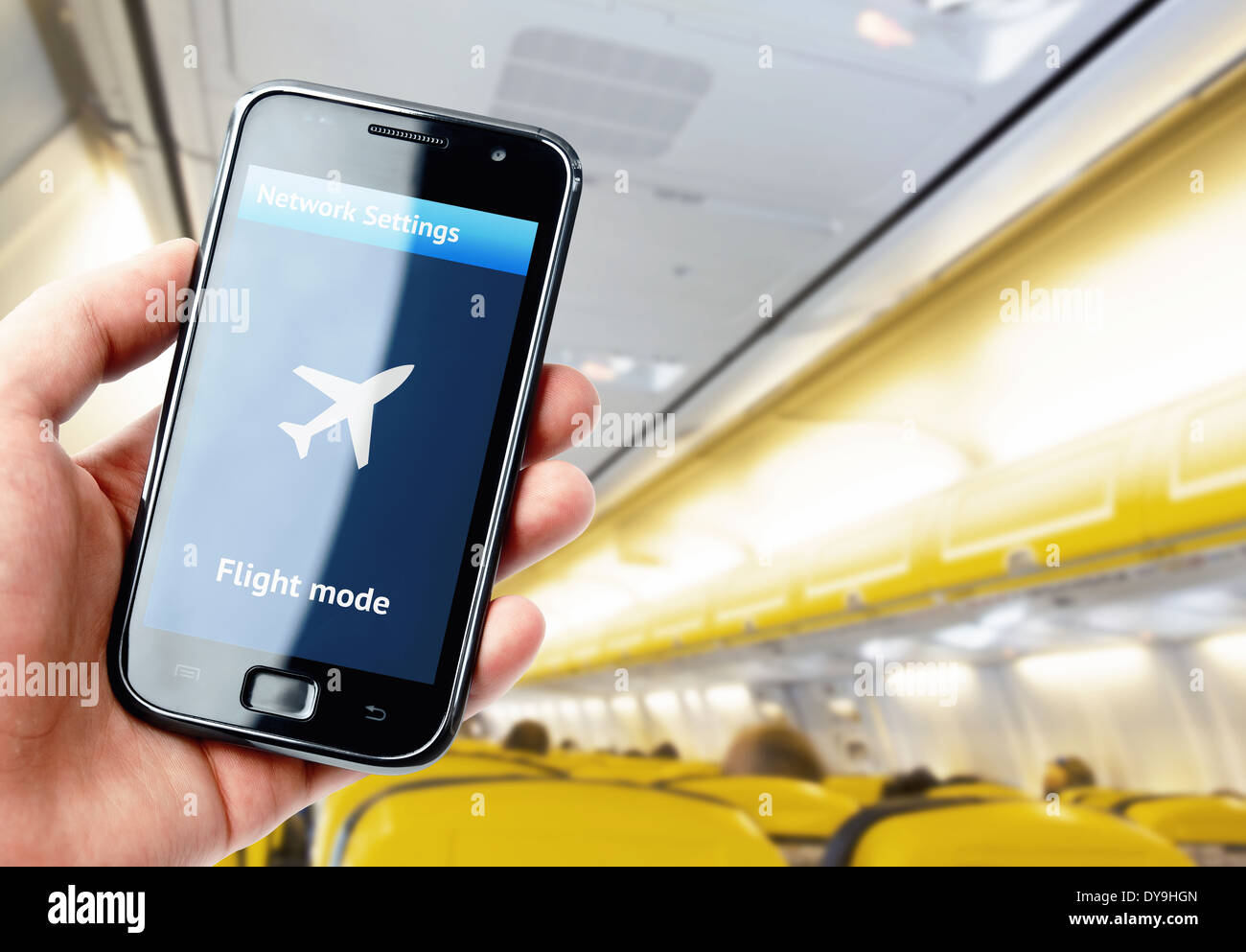 Hand holding smartphone inside the plane with flight mode activated ...