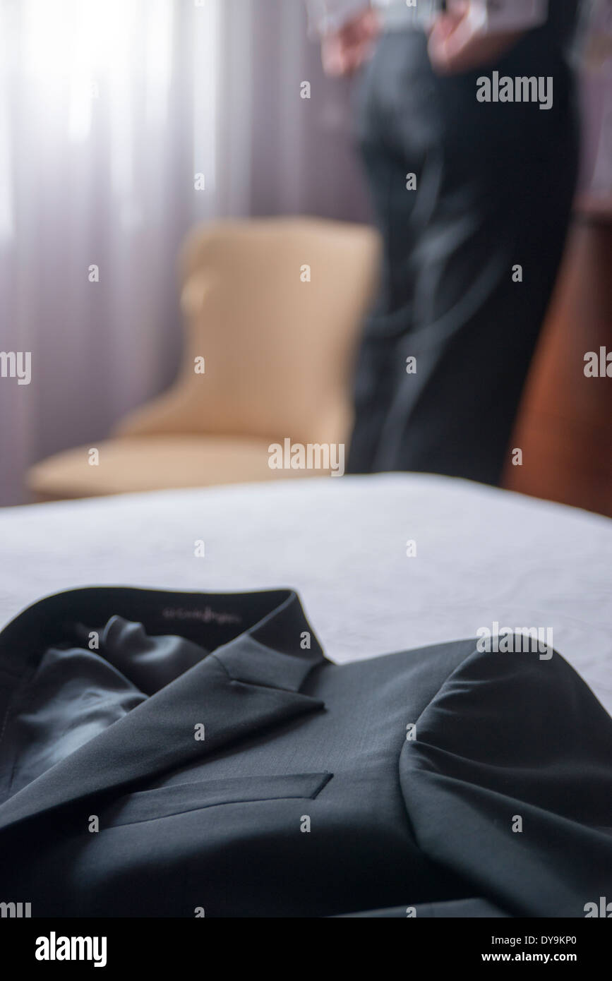 Detail of American boyfriend suit jacket. Man dressing in background ...