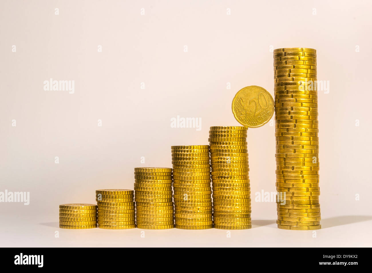 Yellow coins lined up from short to tall stacks with blank background ...