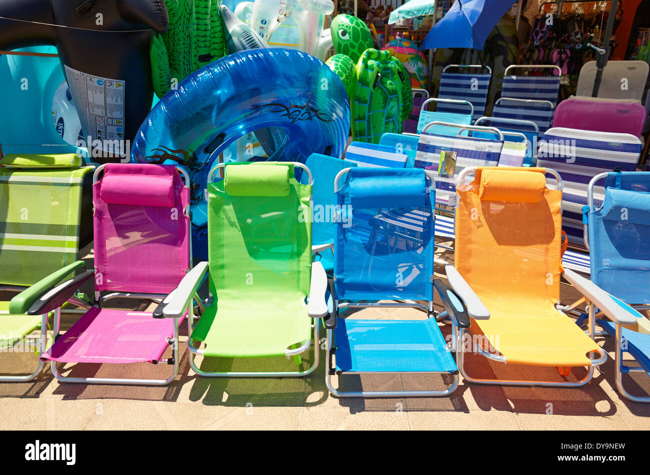 Assorted color beach chairs and liloes at a beach shop. Denia. Alicante ...