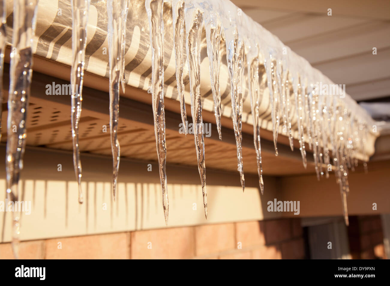 icicles hanging off eavestrough on roof of house Stock Photo - Alamy