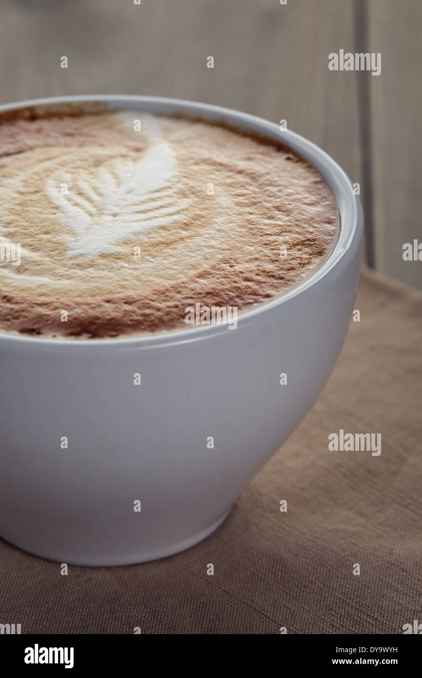 fresh cappuccino cup with simple latte art, on wood table shalow dof ...