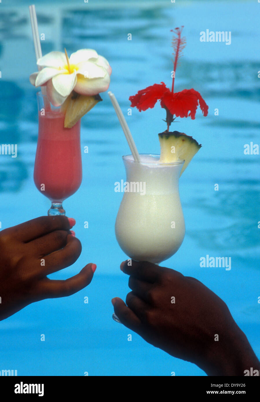Two black hands holding tropical fruit-juice cocktails, Seychelles ...