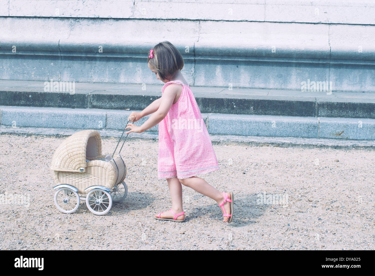 Little girl pushing miniature baby carriage Stock Photo - Alamy