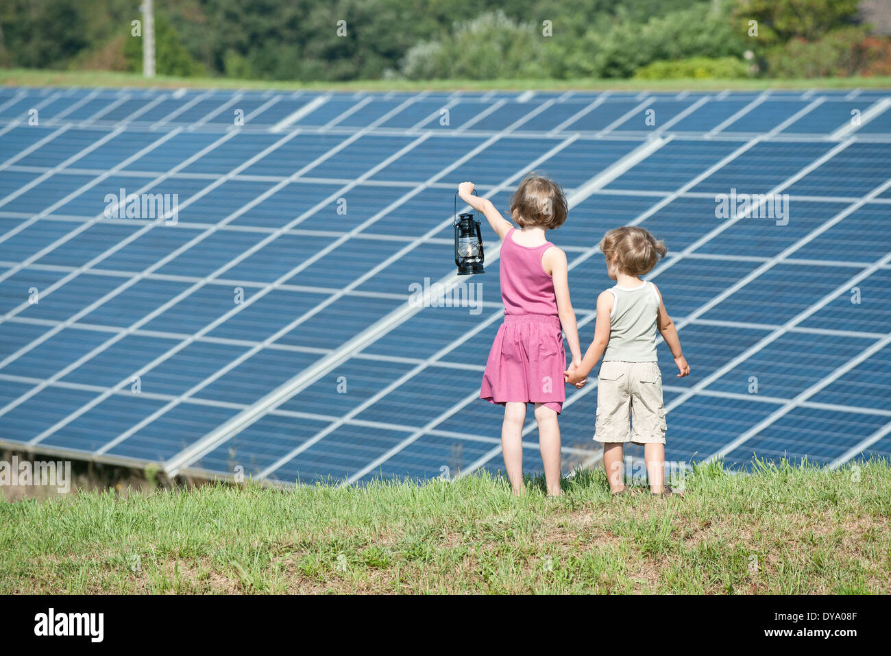 Children standing together in front of solar panels, girl holding old ...