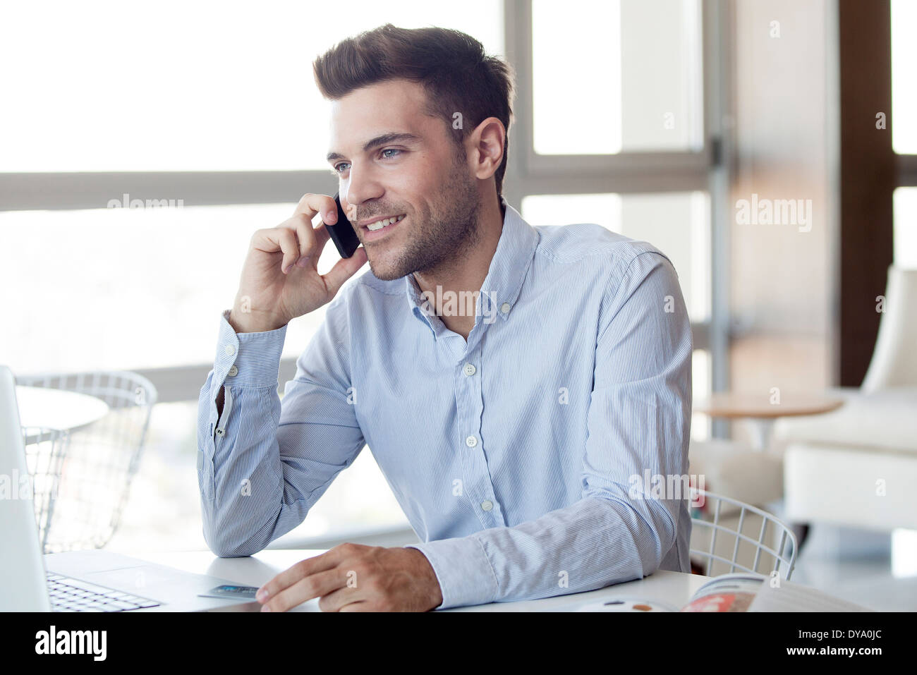 Man making cell phone call while using laptop computer Stock Photo - Alamy