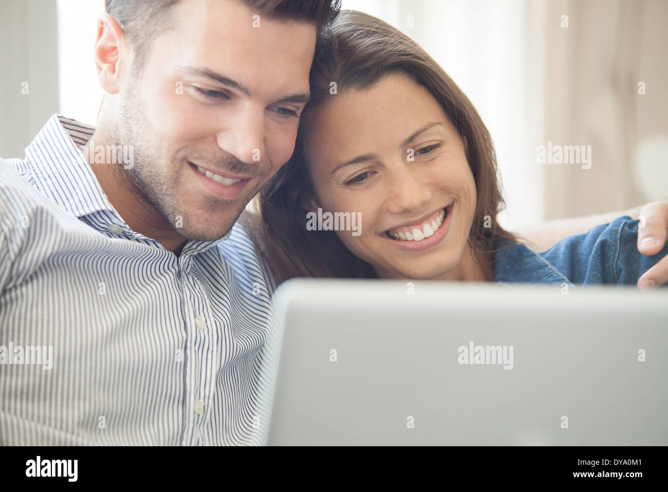 Couple relaxing at home looking at laptop computer together Stock Photo ...