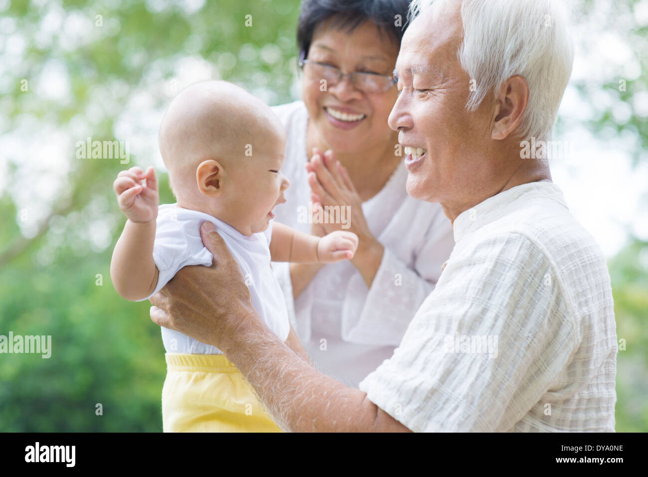 Happy Asian grandparents playing with baby grandchild at outdoor garden ...