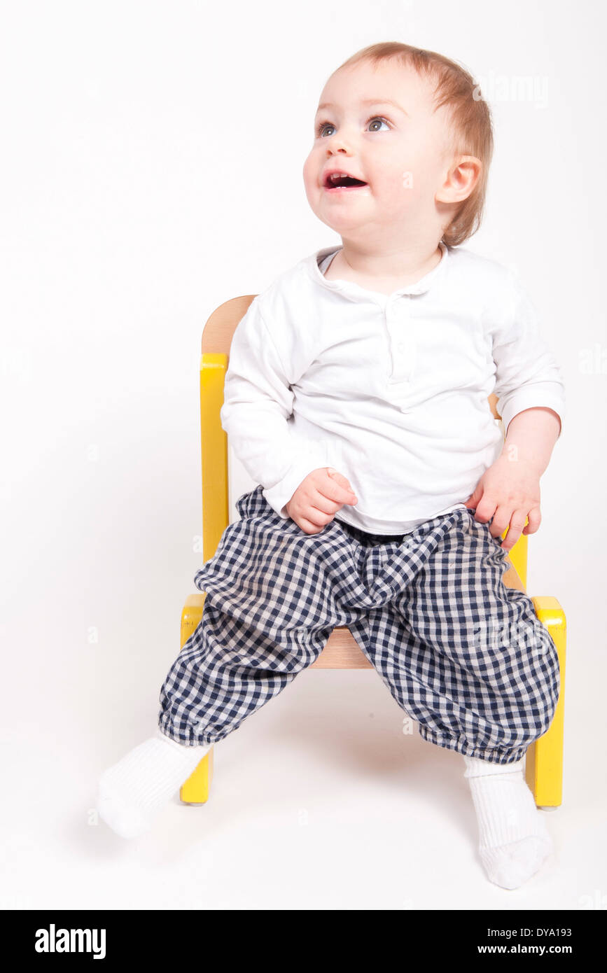 Baby boy sitting in chair, looking up, portrait Stock Photo - Alamy