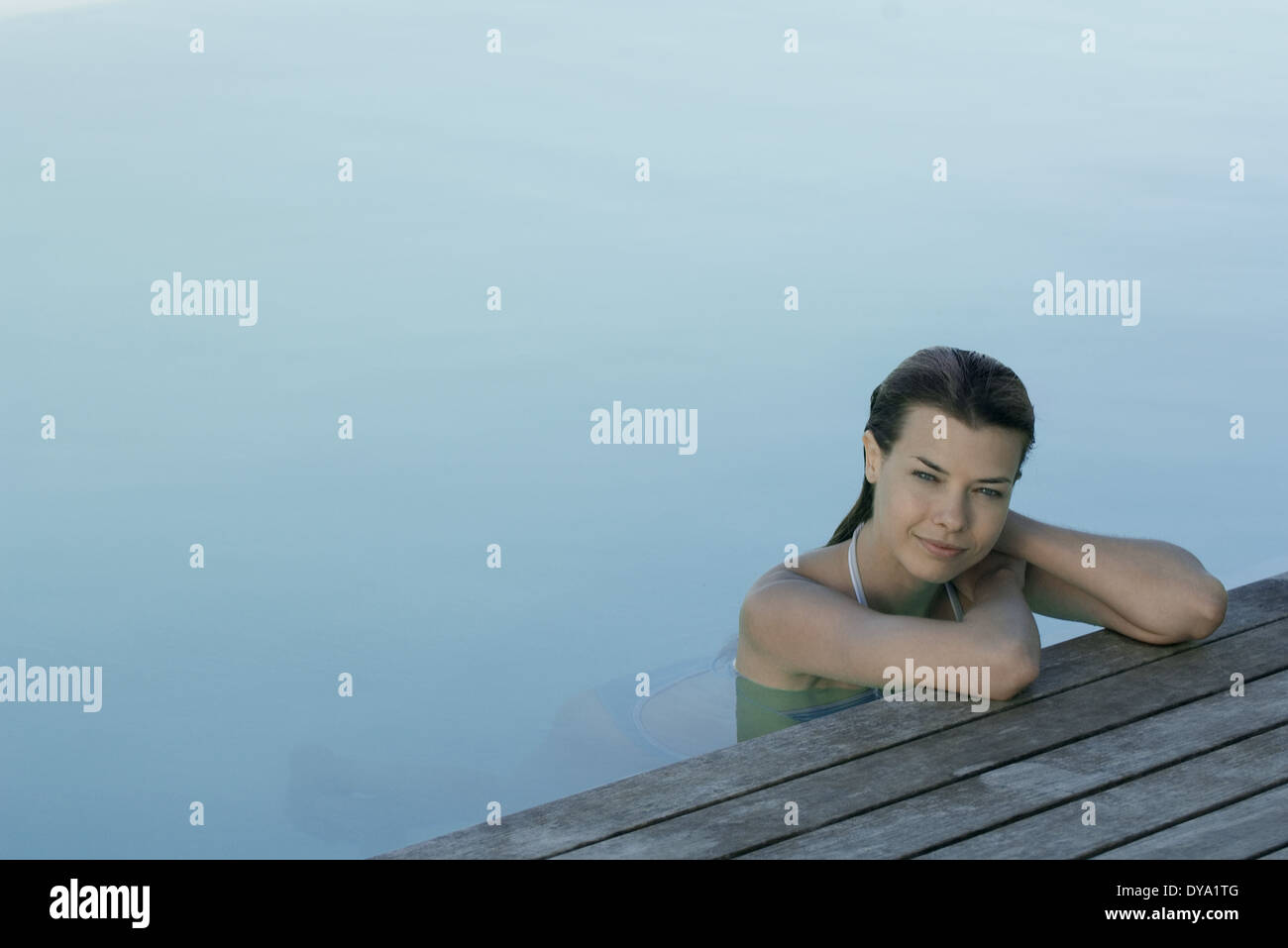 Woman in pool leaning against deck, looking at camera Stock Photo - Alamy