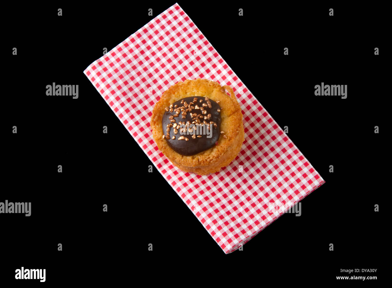 Home baked chocolate iced individual sponge cake on a gingham patterned ...