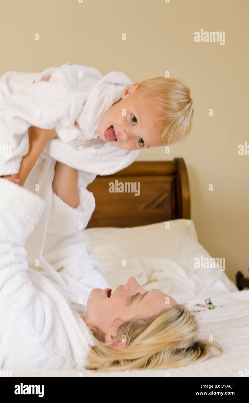 Female and toddler boy playing on bed in bathrobes hi-res stock ...