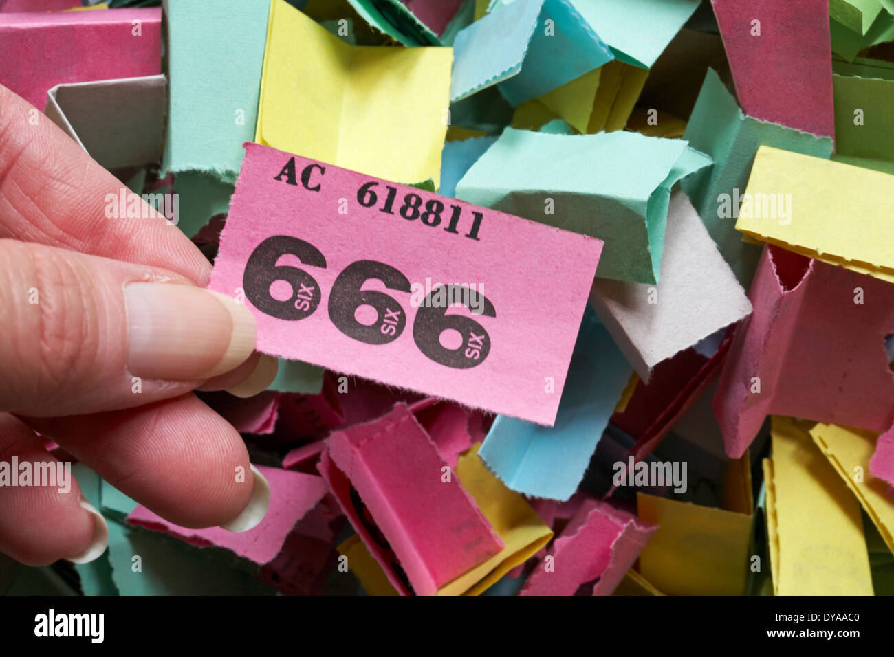 pile of different coloured raffle tickets with hand picking winning ...