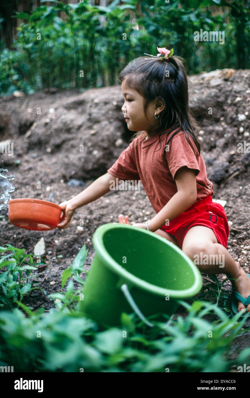 Phillippines young girl kneeling planting seeds earth sieve bucket ...