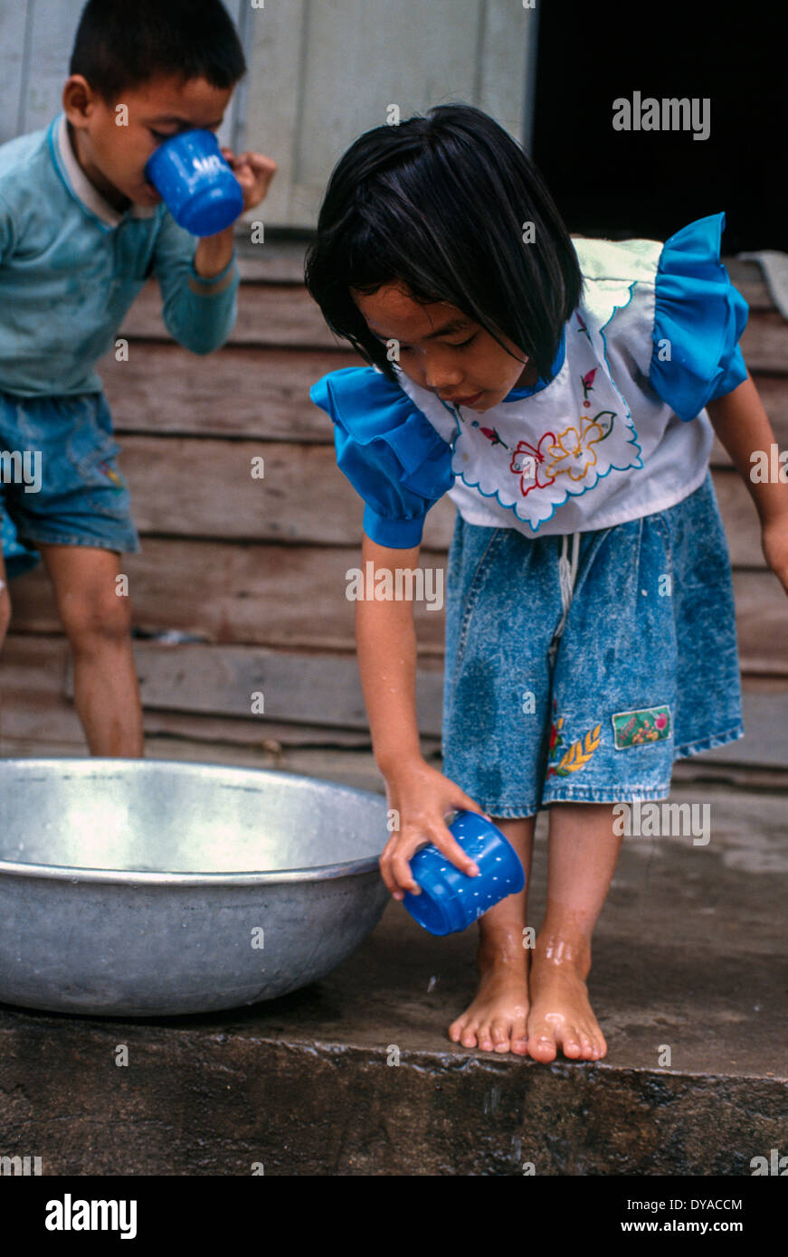 Phillippines girl bending washing feet boy drinking water metal bowl ...