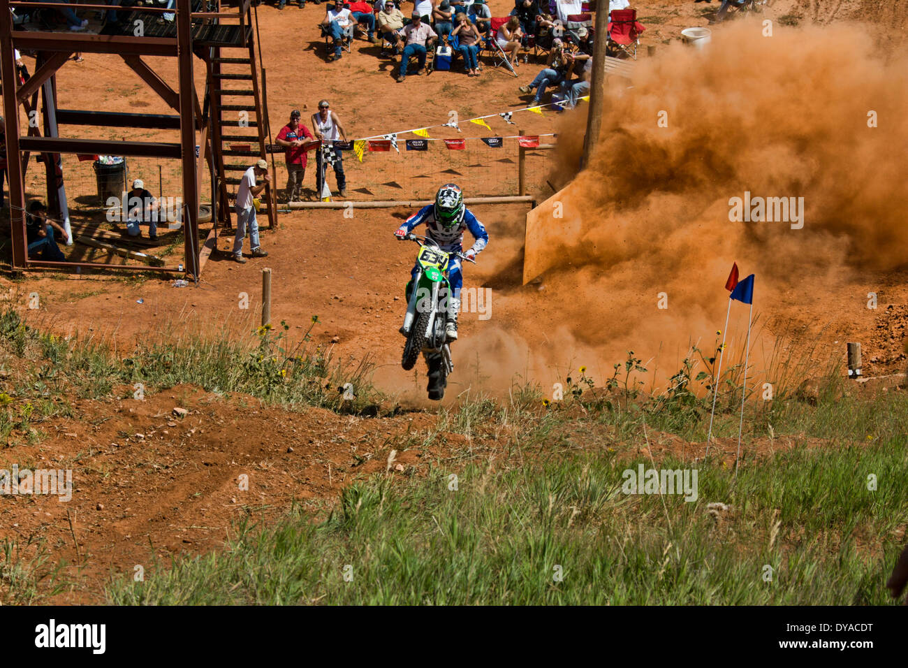 Motorcycle rider racing up the hill with a large cloud of dust in his ...