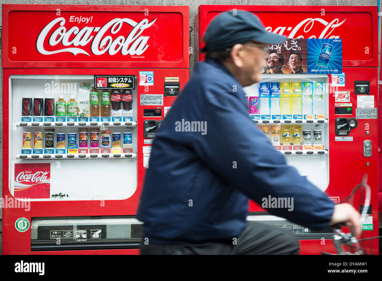Man riding bicycle past drink vending machines at Nishiki market in ...