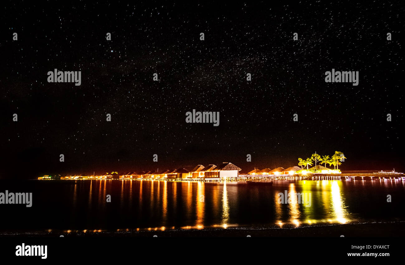 Night on tropical resort, many little beach houses glowing bright ...