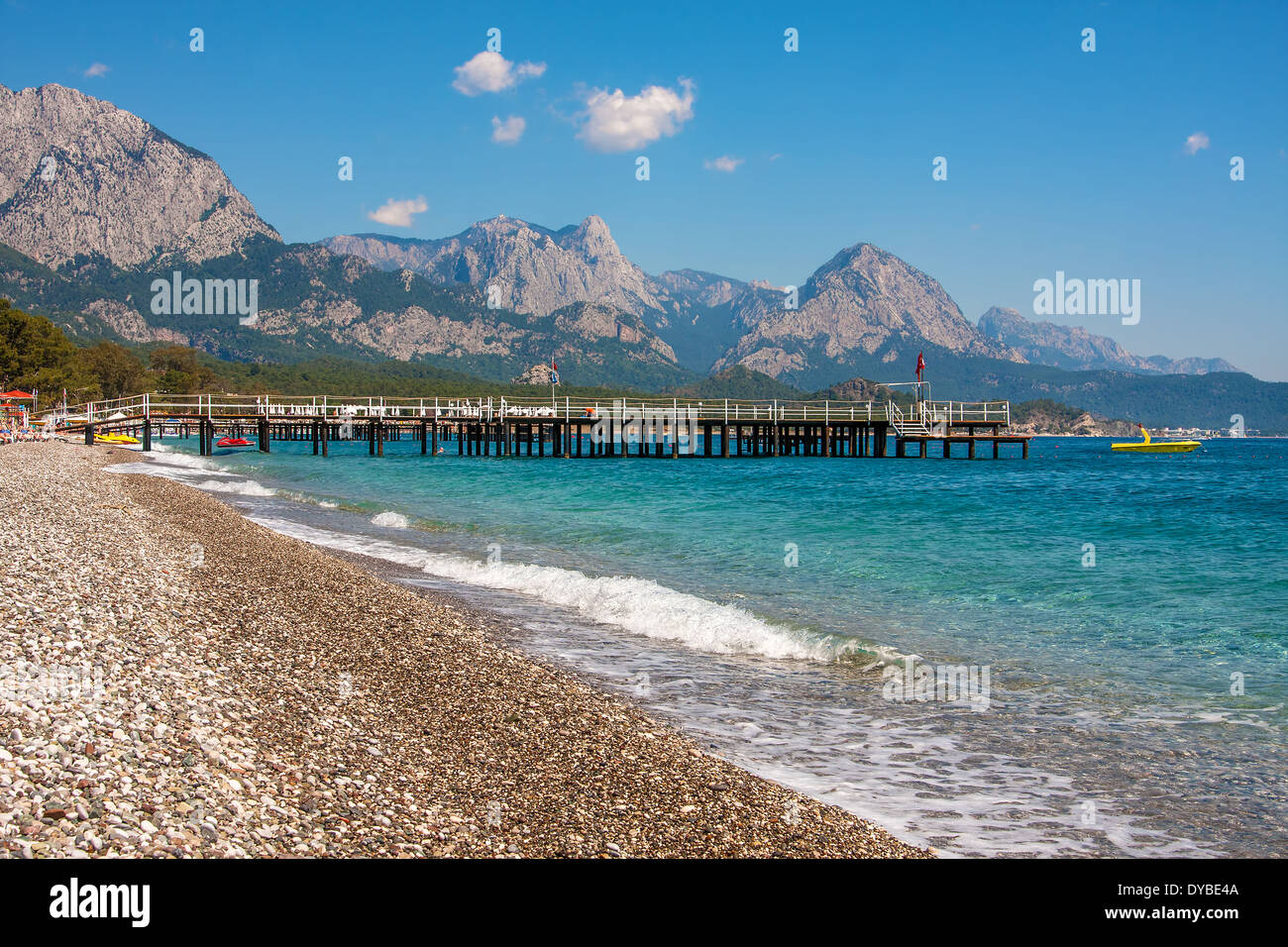 Pier on shingle beach and aquamarine water in popular touristic resort ...