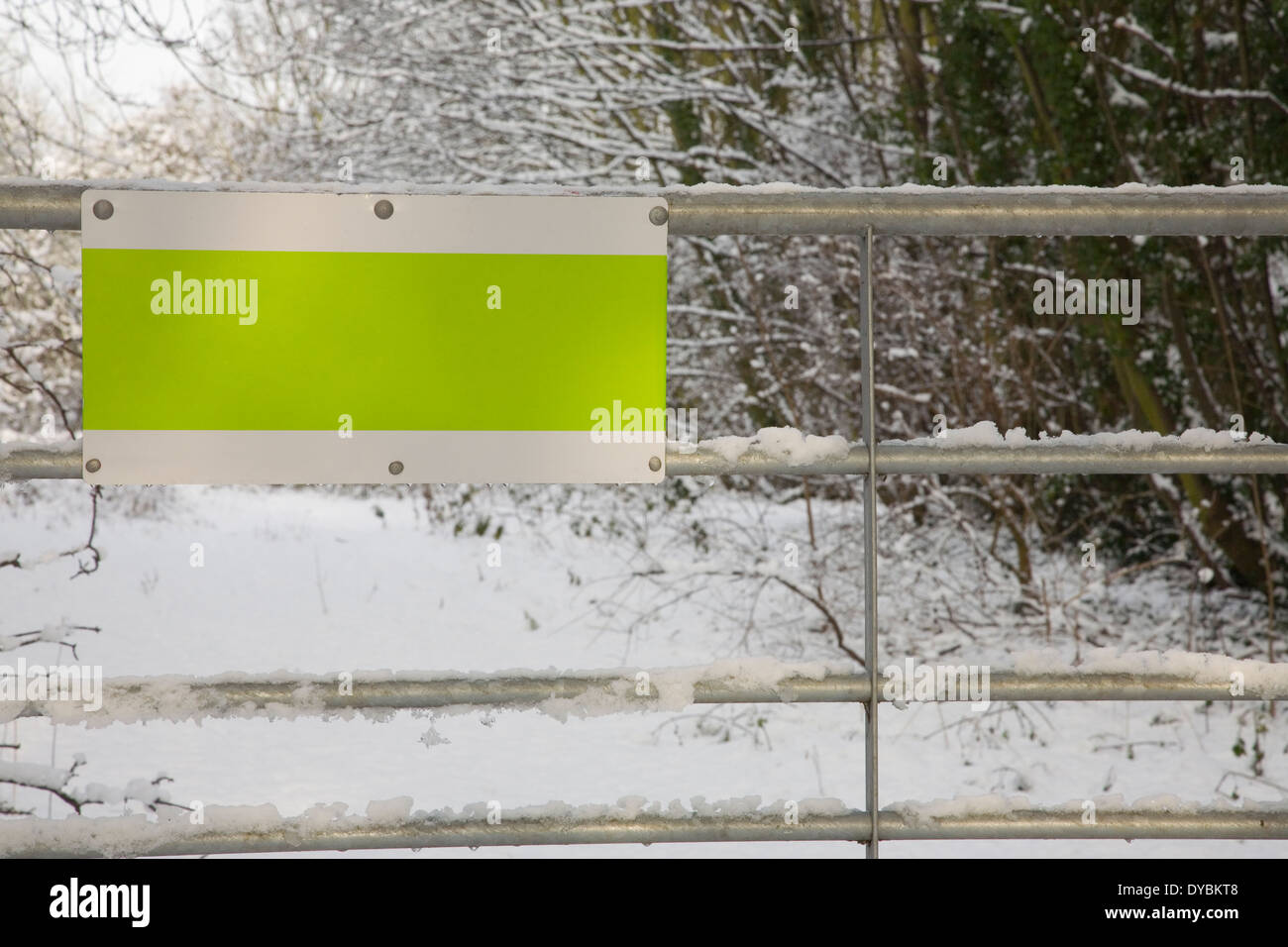winter snow scene showing a Field metal Gate with a blank sign to add ...
