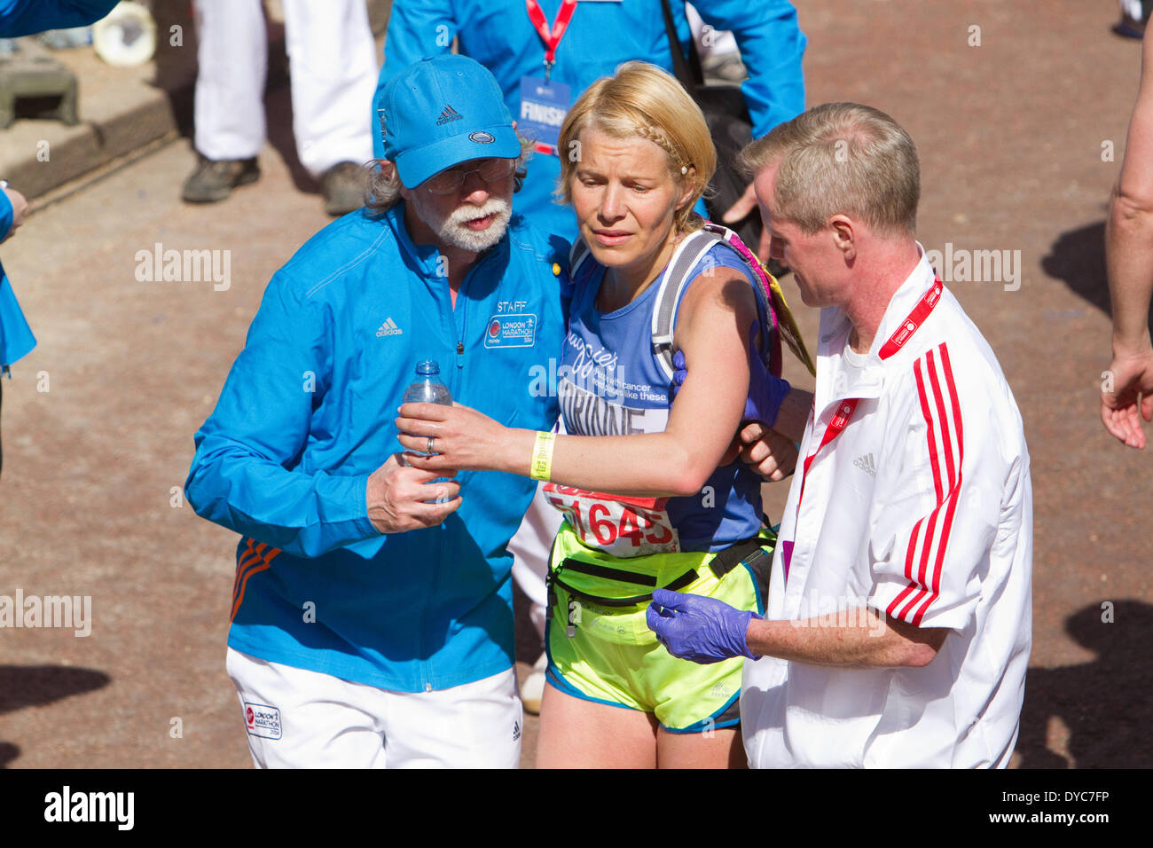 London,UK,13th April 2014,A female runner is helped to walk after ...