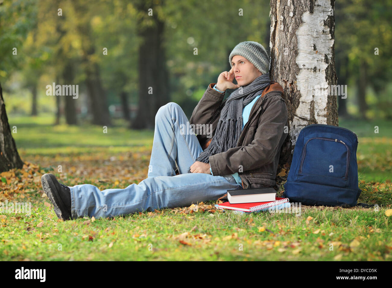 Male student thinking, seated by a tree outdoors Stock Photo - Alamy