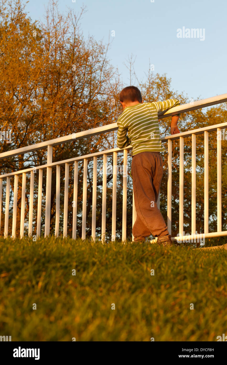 Young boy outdoors holding onto railing Stock Photo - Alamy