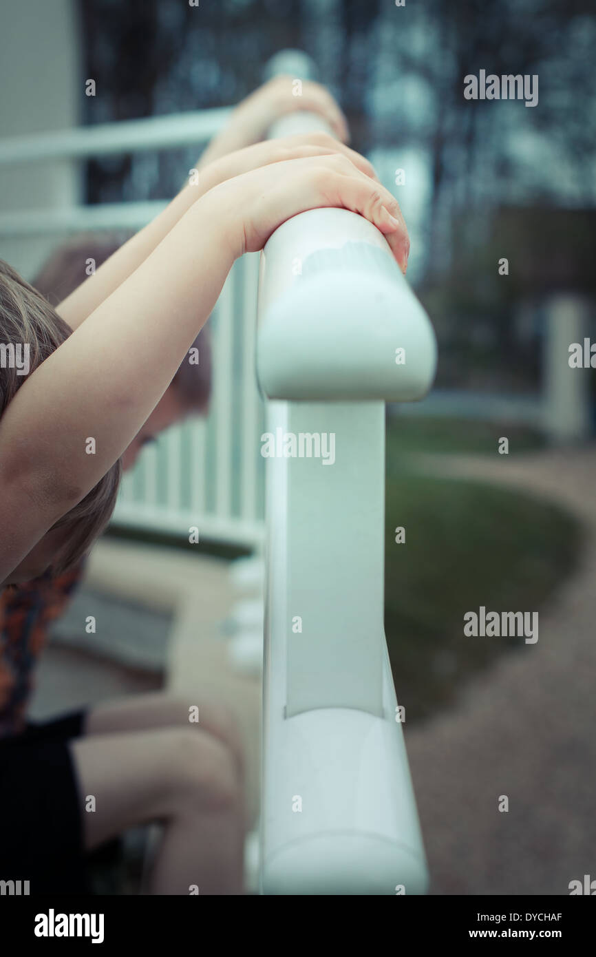 Two young boys outdoors hanging onto a railing Stock Photo - Alamy