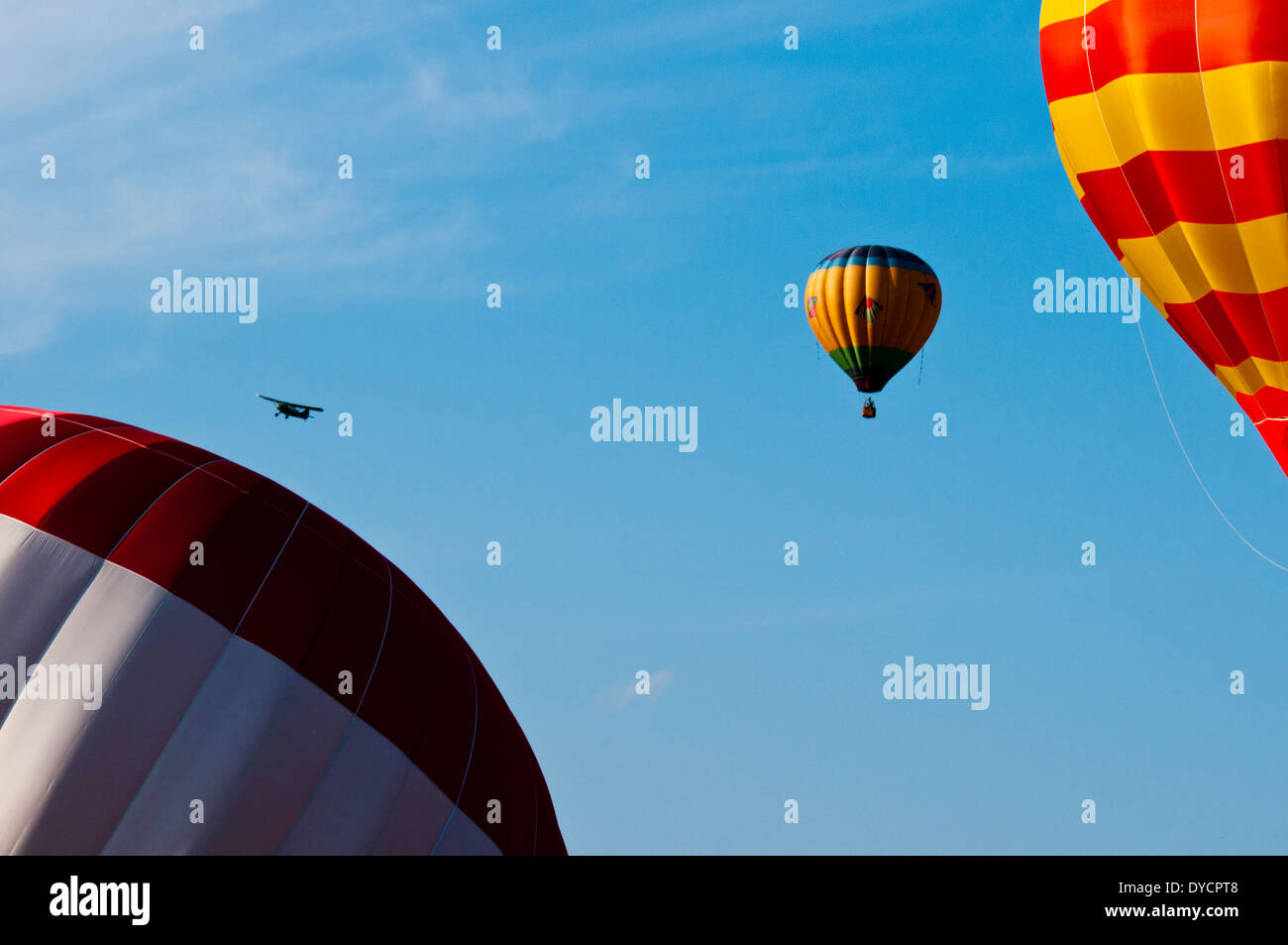 A hot air balloons rising with a plane doing aerial stunts in front a ...