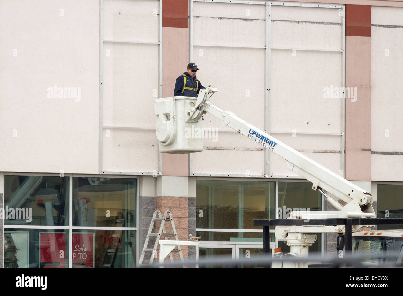Man on cherry picker being raised in preparation of putting up a sign ...