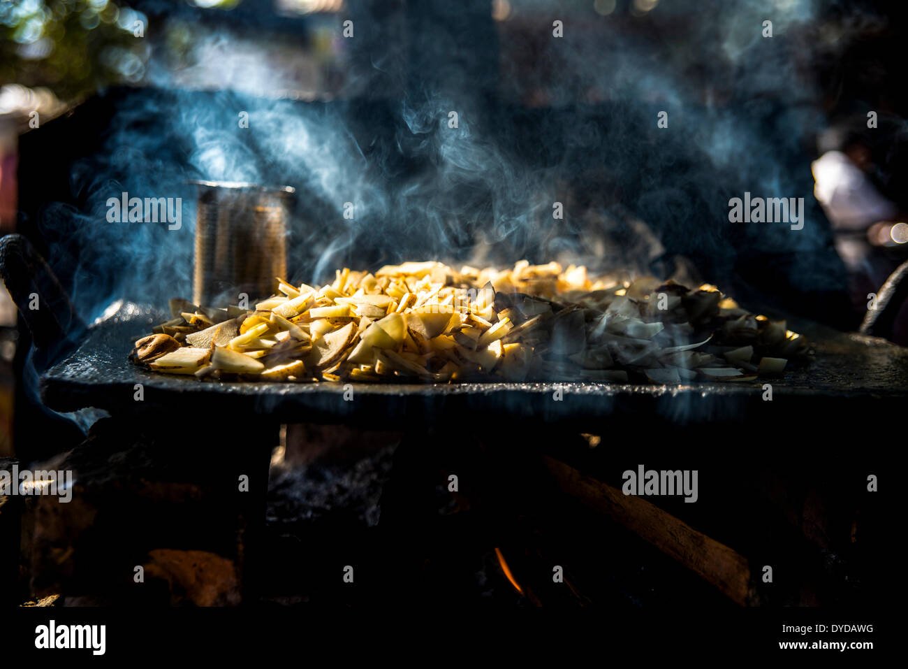 Crisps frying over an open fire, sun rays penetrating the smoke, street ...