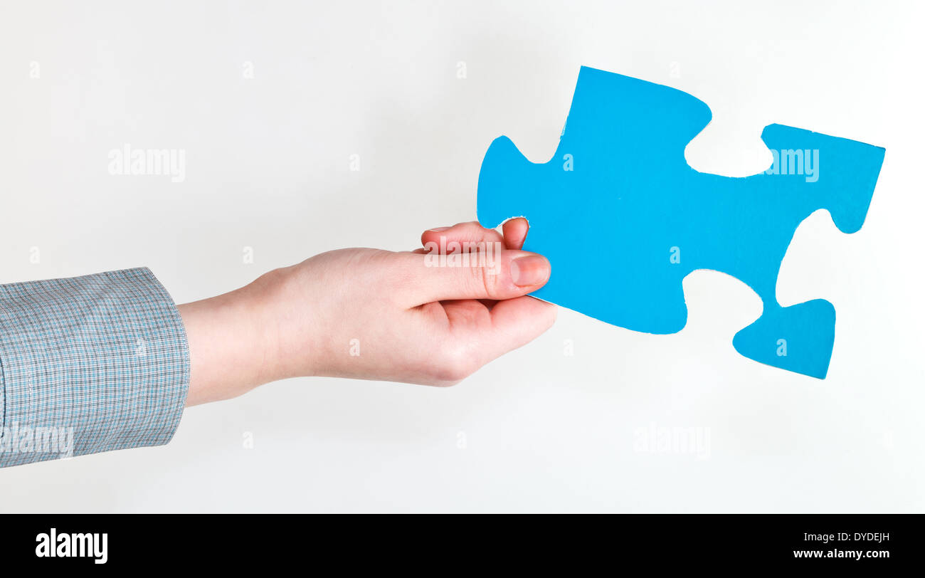 blue puzzle piece in female hand on grey background Stock Photo - Alamy