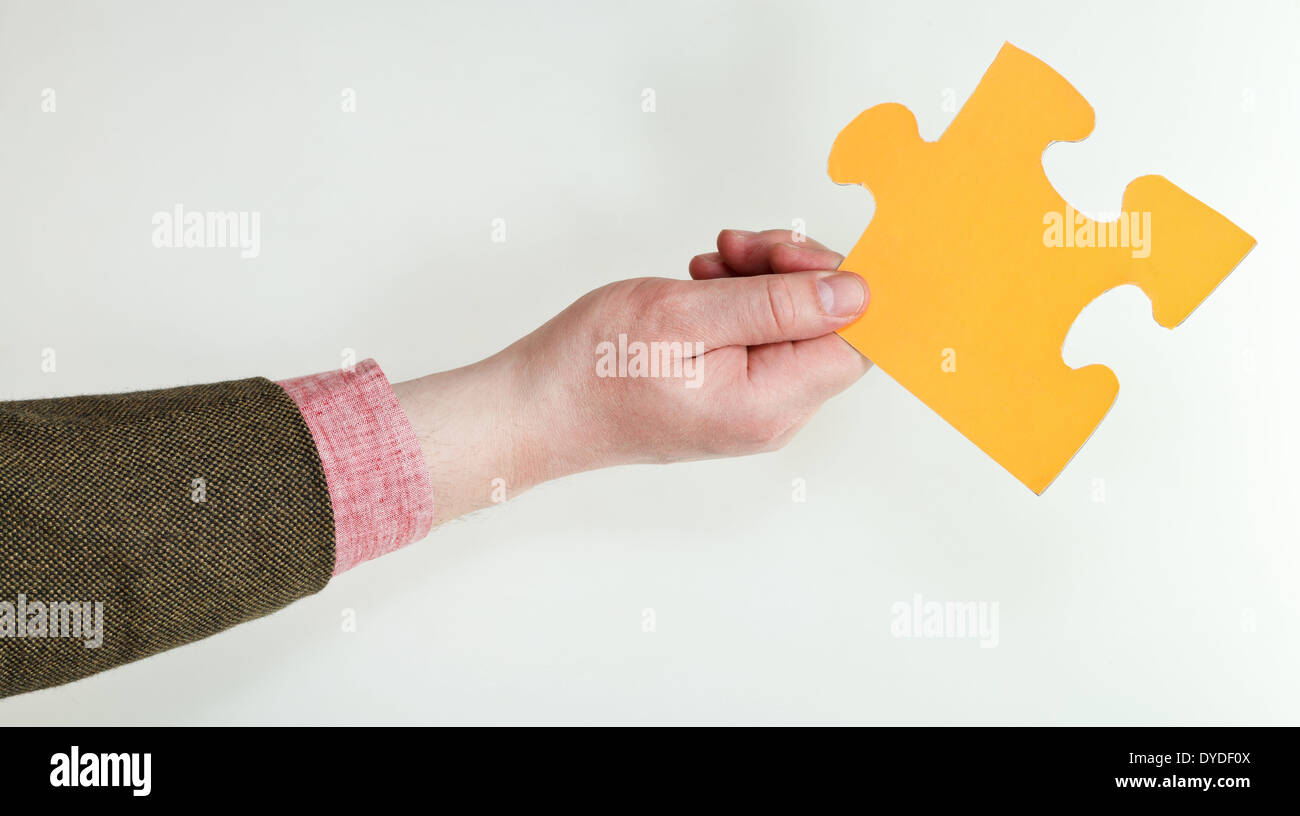 yellow puzzle piece in male hand on grey background Stock Photo - Alamy
